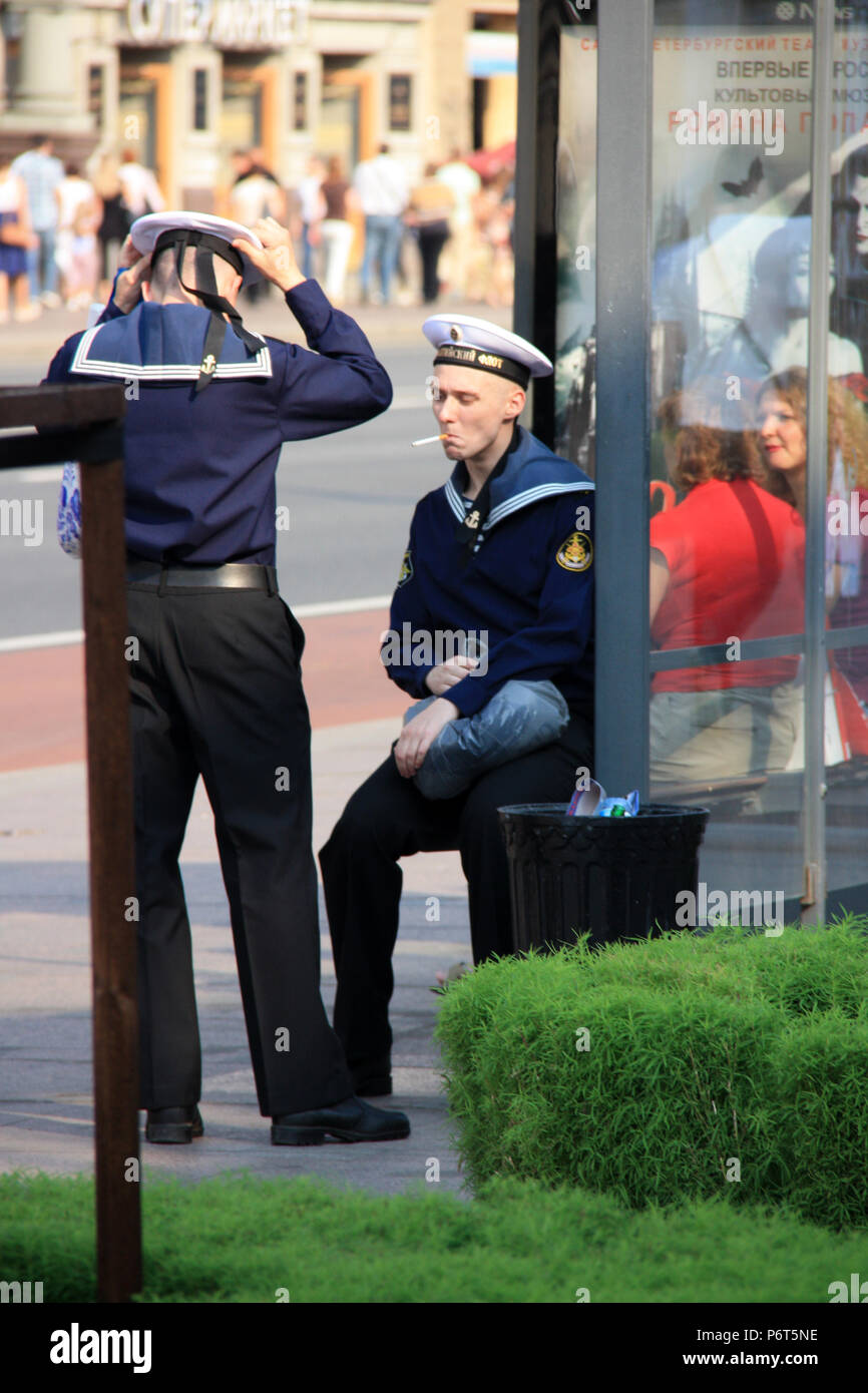 Two young sailors of the Russian Navy smoking while waiting for the bus ...