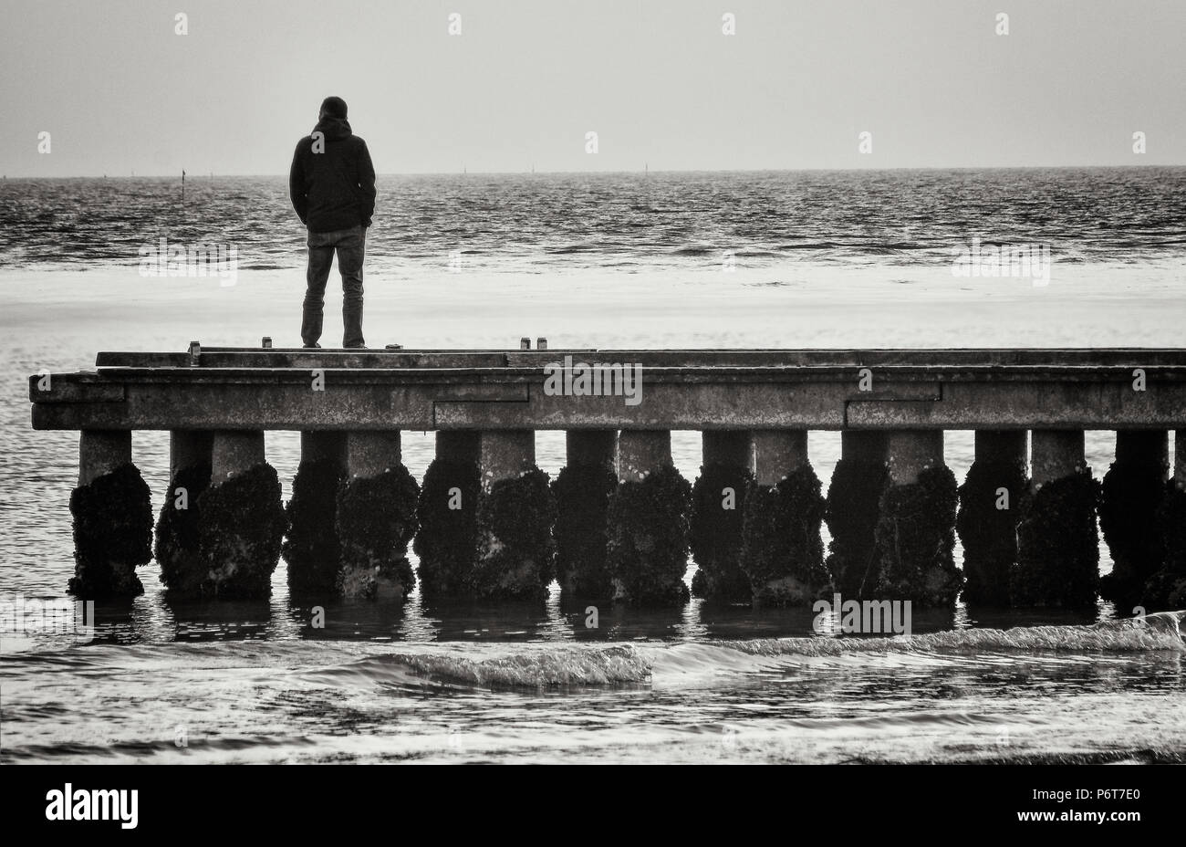 Lonely man standing on a pier staring at the sea Stock Photo - Alamy