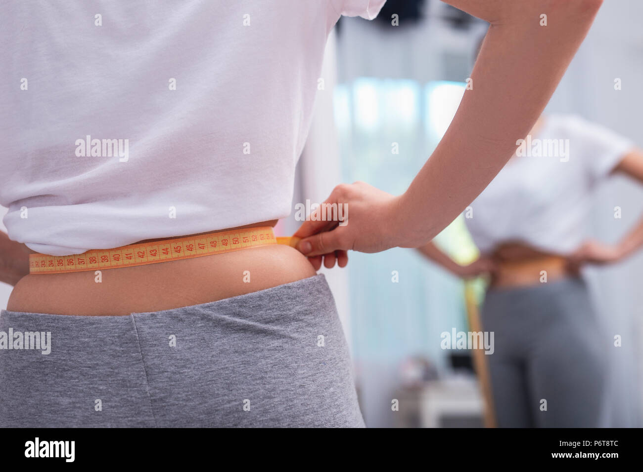 Young female hands measuring waist Stock Photo - Alamy