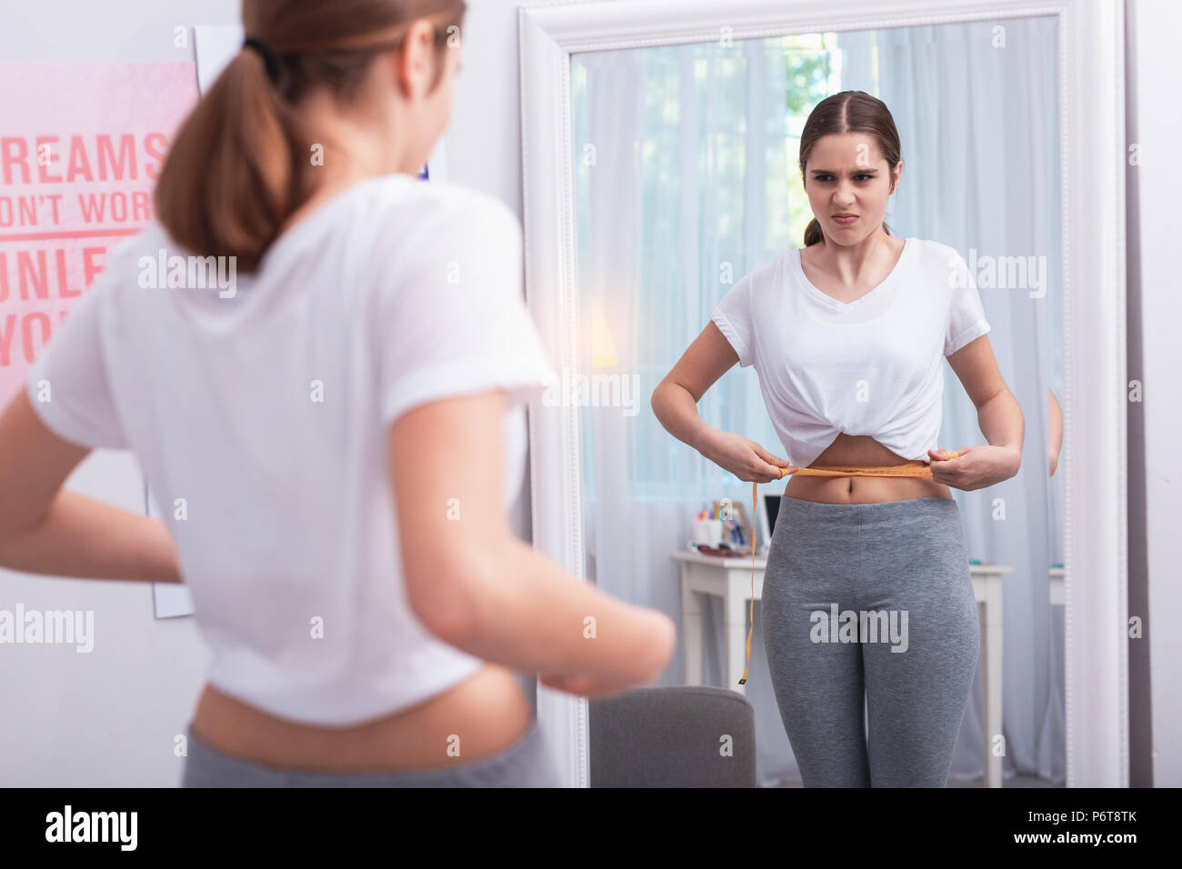 Displeased teen girl controlling weight gain Stock Photo - Alamy