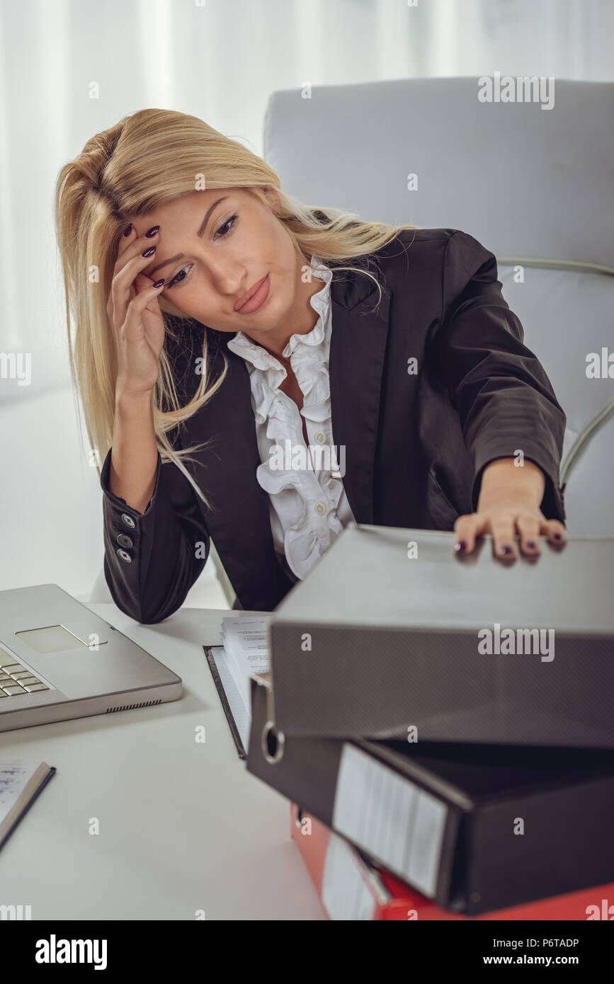 Young tired and worried business woman sitting in the office. There is ...