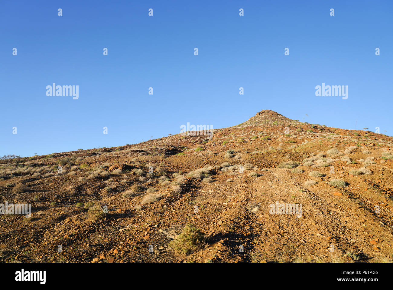 Stony pinnacle with scrubby vegetation under blue sky in Namibia Stock ...