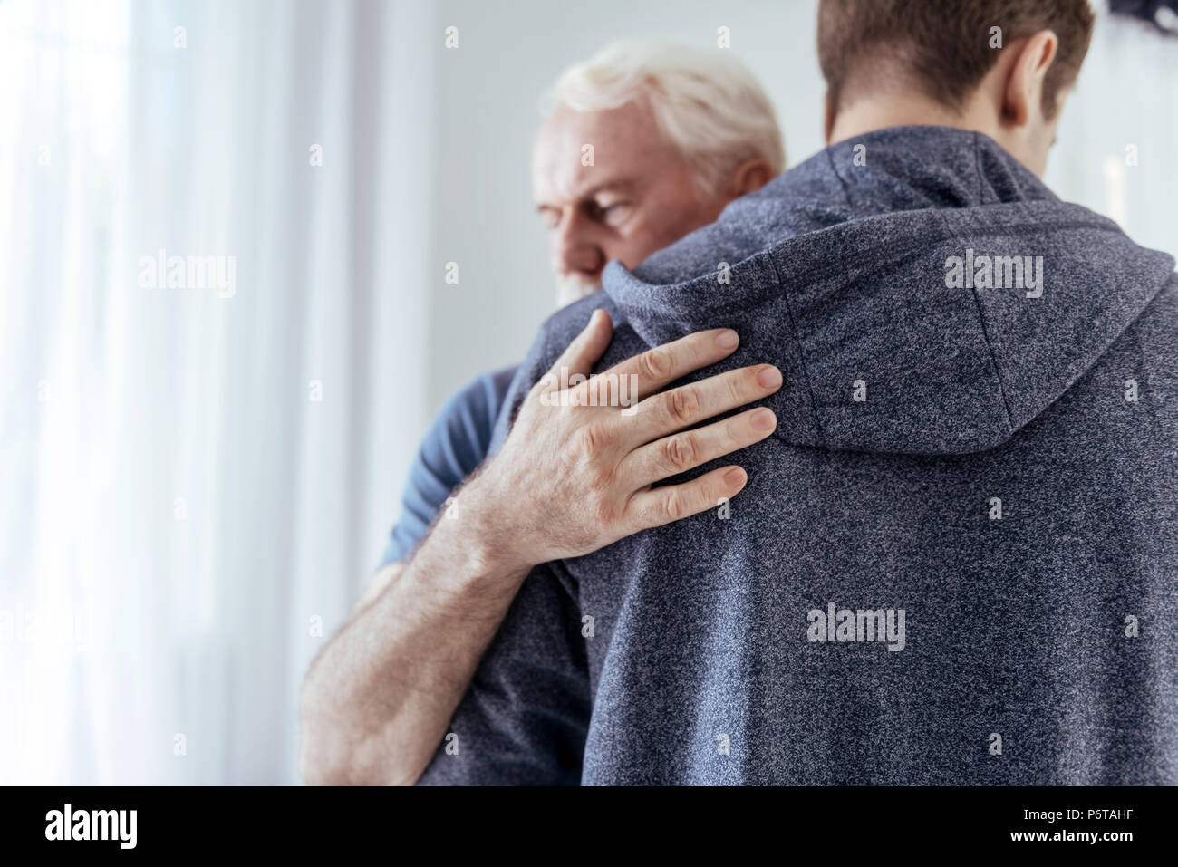 Reflective senior man hugging man Stock Photo - Alamy