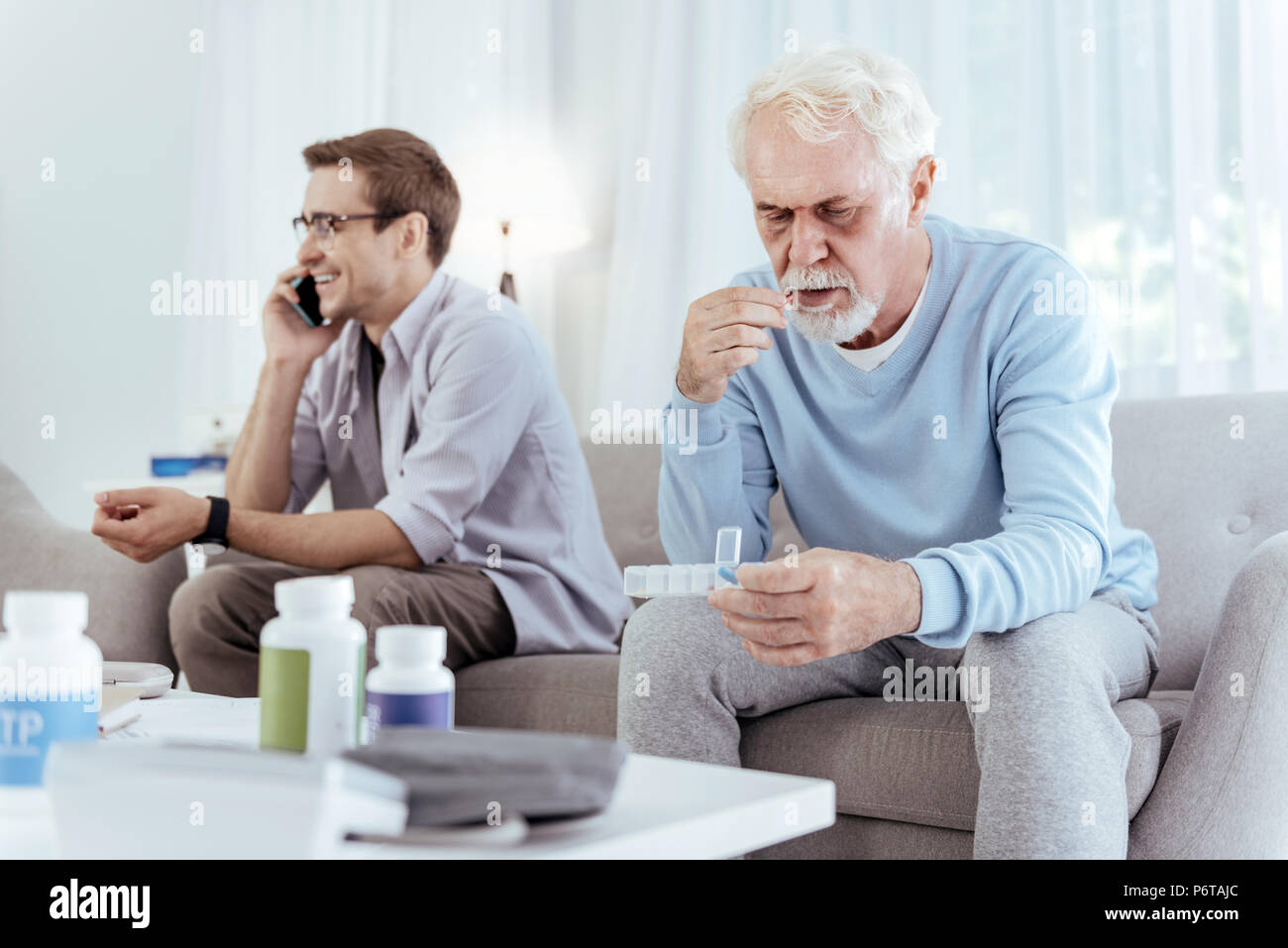 Satisfied male caregiver ignoring senior man Stock Photo - Alamy