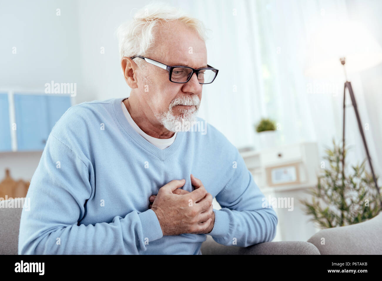 Focused senior man having heart problem Stock Photo - Alamy