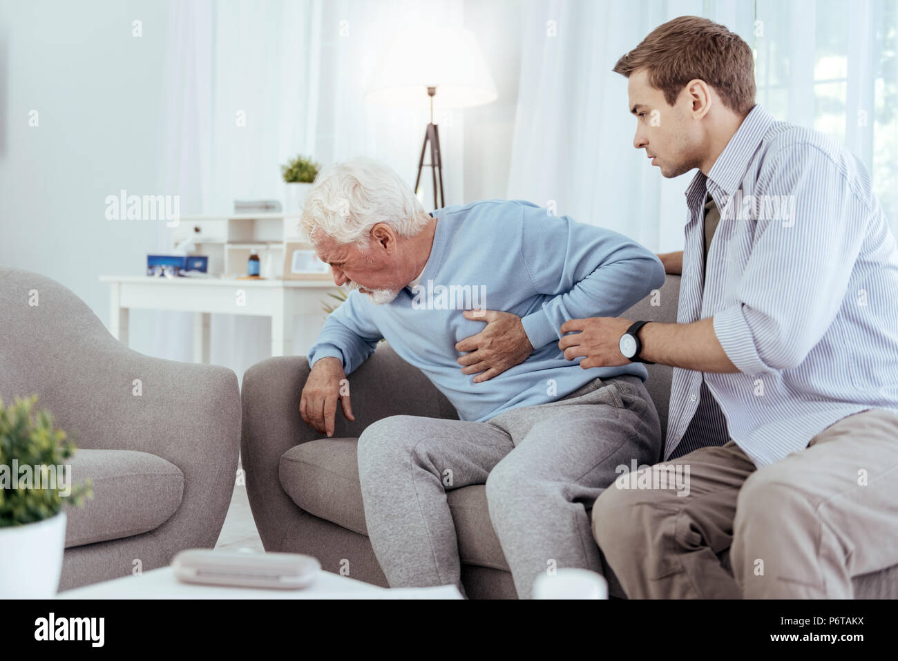 Concerned man helping senior man Stock Photo - Alamy