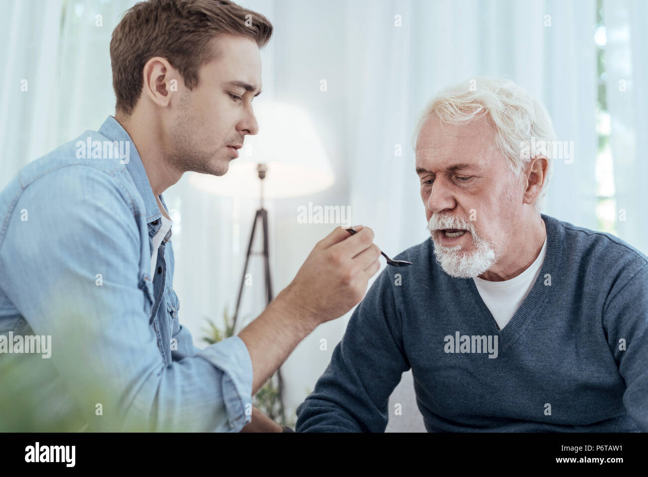 Focused man feeding senior man Stock Photo - Alamy