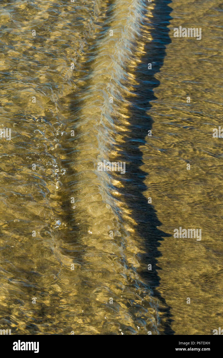 Pattern formed by water rushing back to the ocean as a wave recedes, on ...
