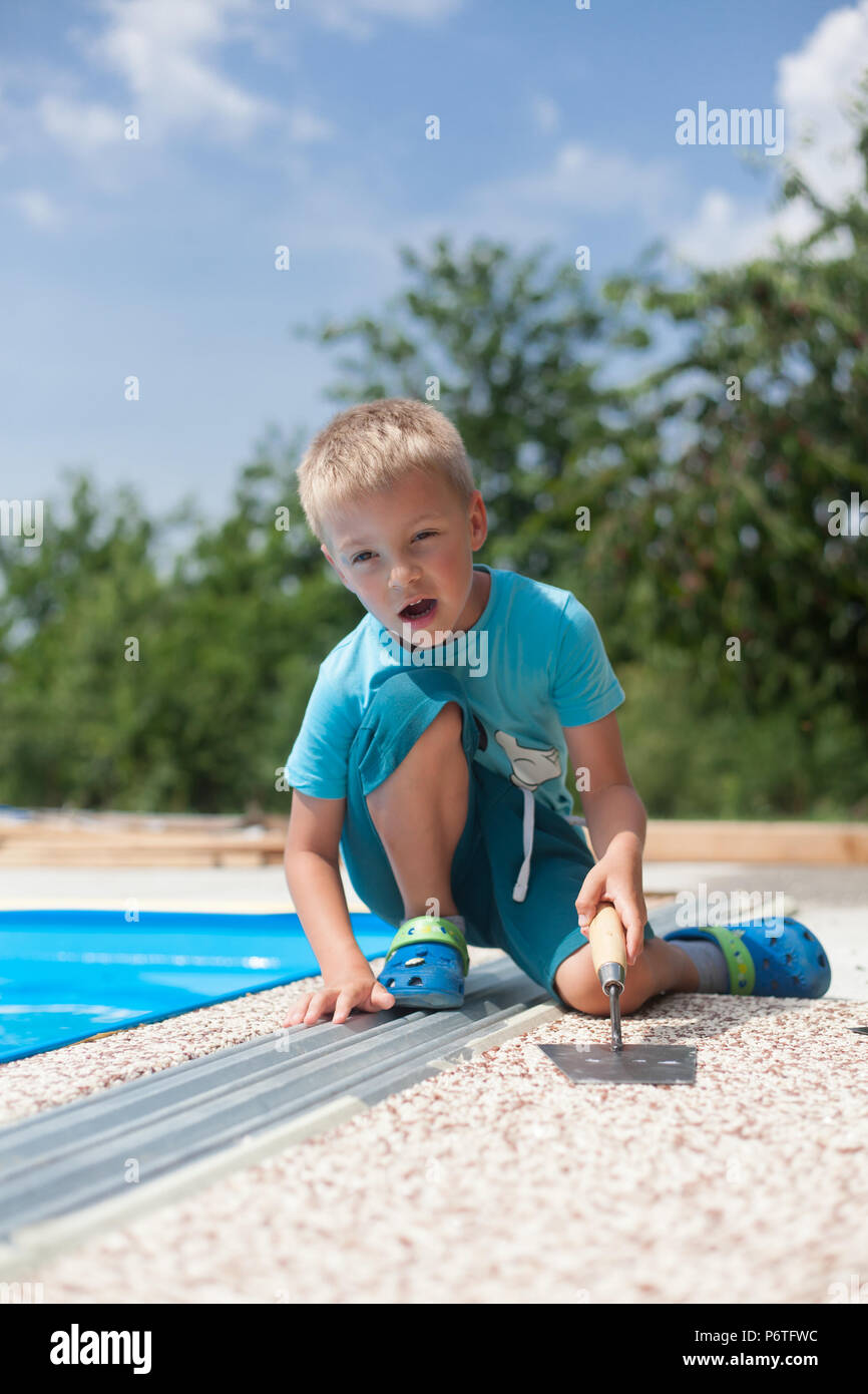 A little boy is working on a new pavement around the pool Stock Photo ...