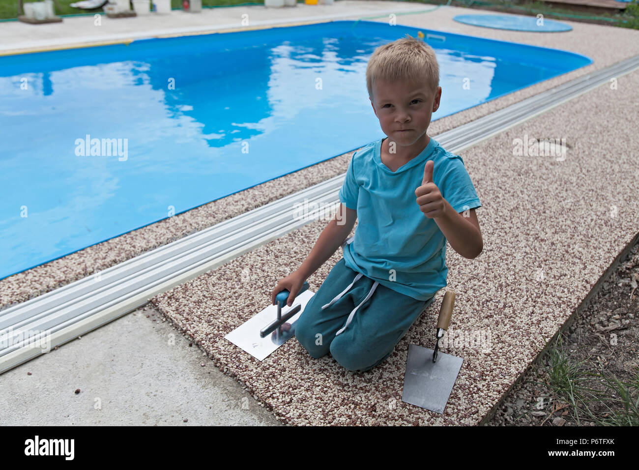A little boy is working on a new pavement around the pool Stock Photo ...