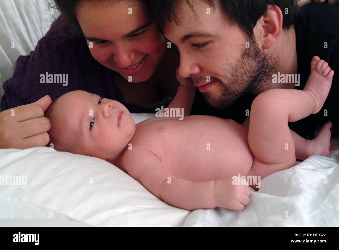 Happy smiling parents looking at their baby adoringly Stock Photo - Alamy