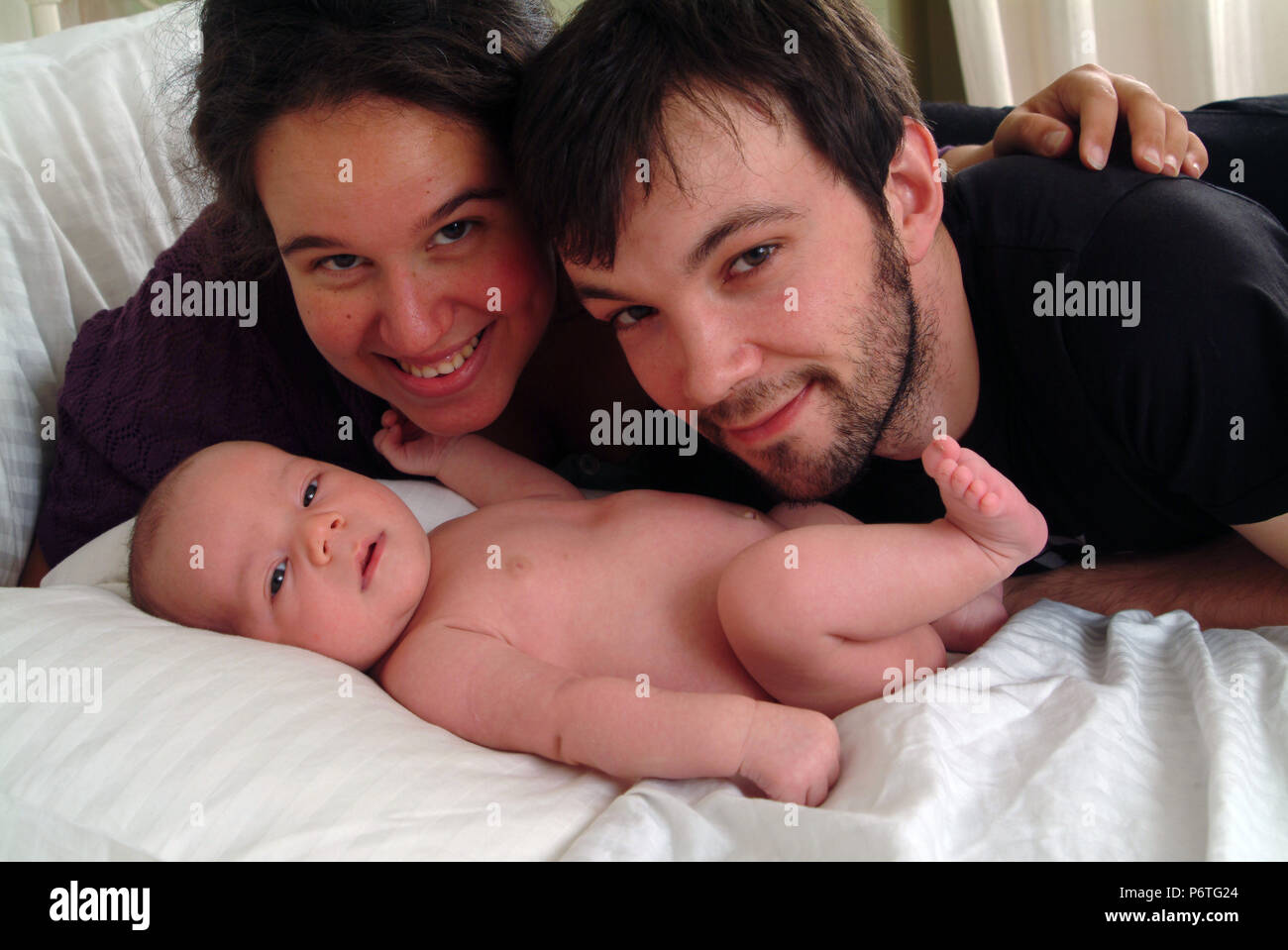 Happy smiling parents looking at their baby adoringly Stock Photo - Alamy