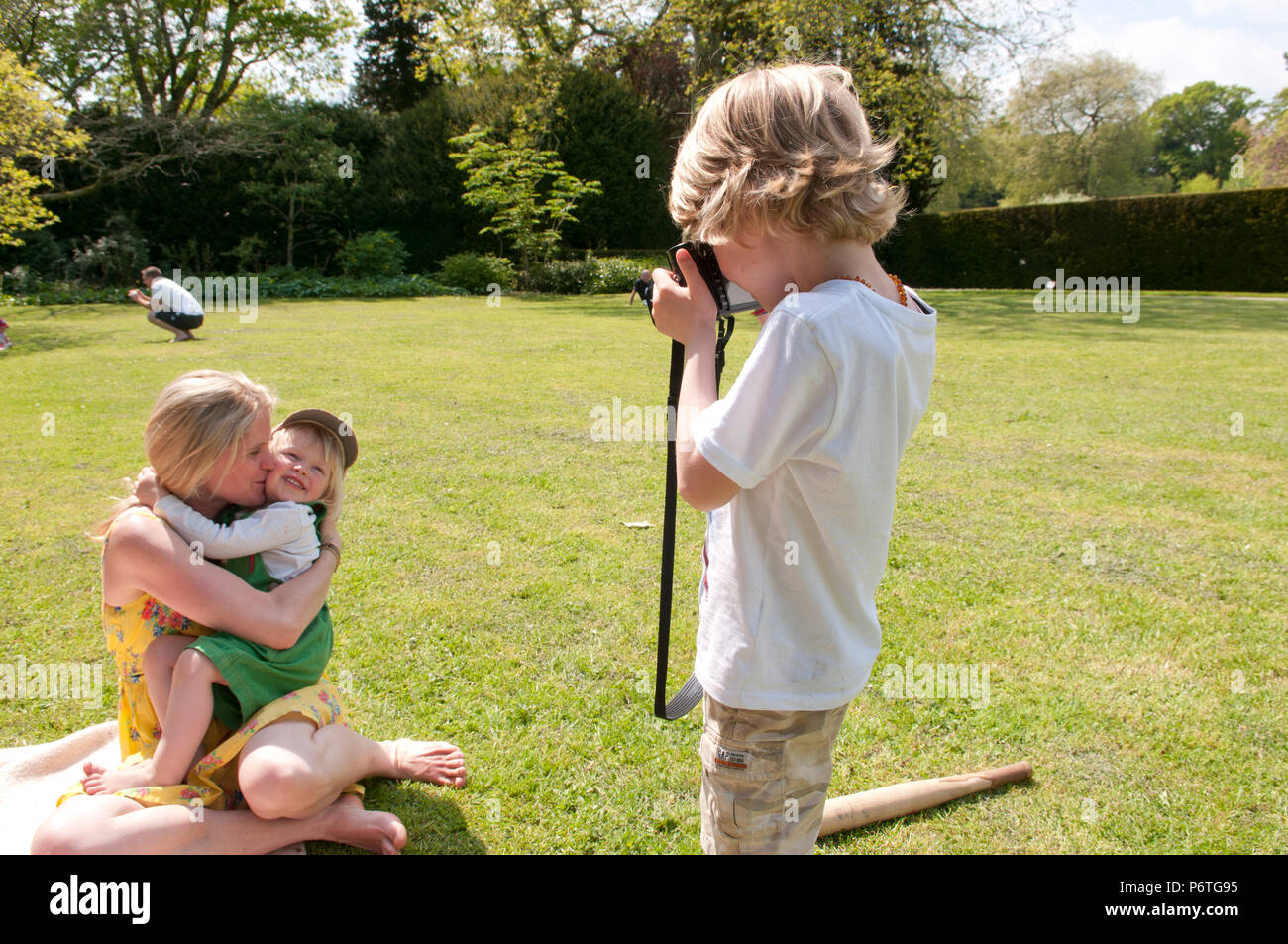 Little boy taking photographs of his mum and sibling Stock Photo - Alamy
