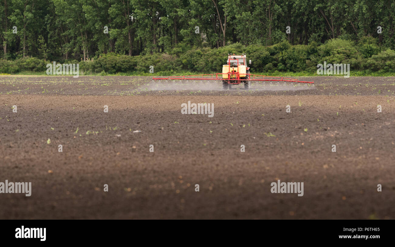 Tractor spraying pesticides on arable fields with sprayer Stock Photo ...