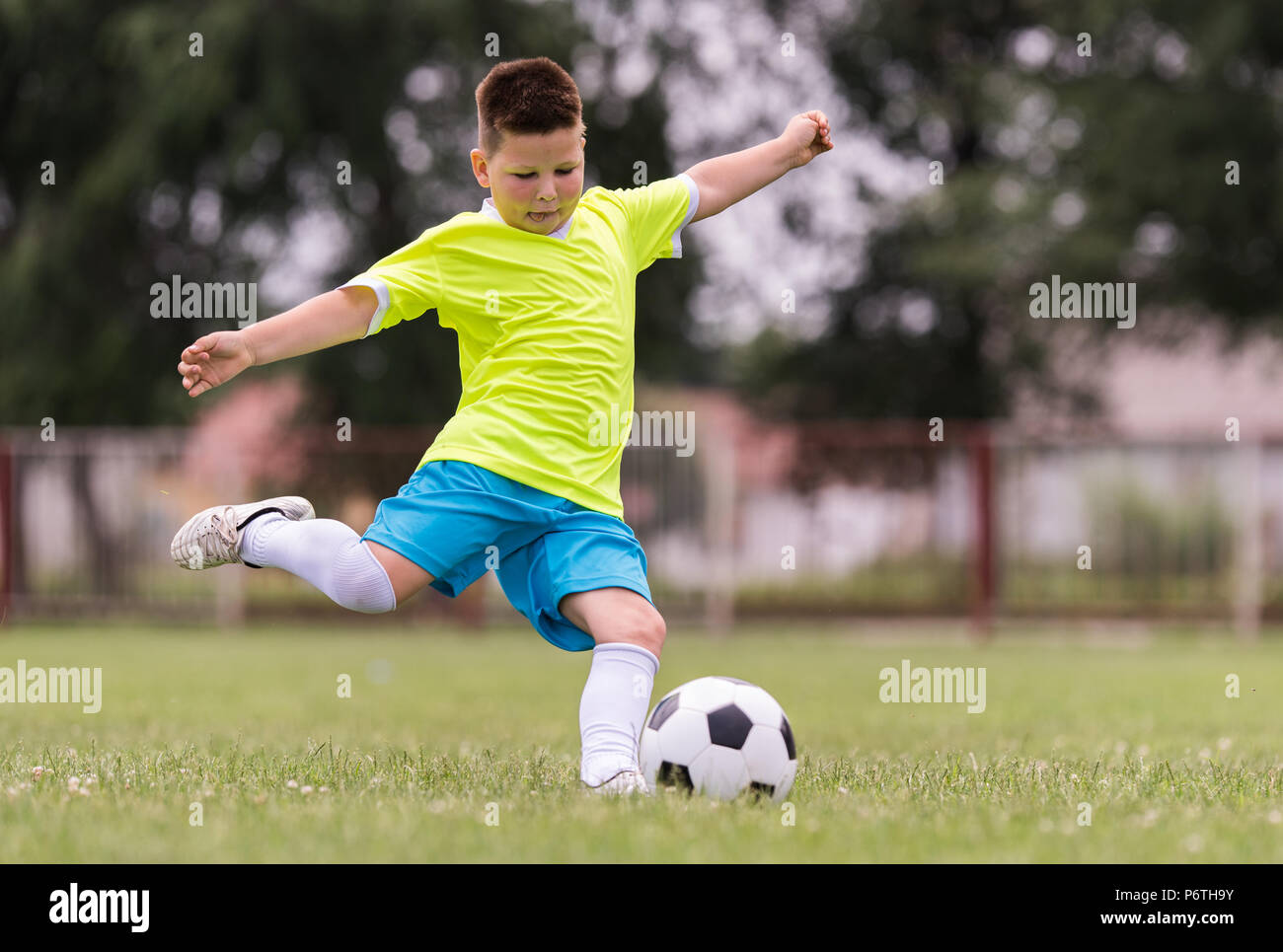 Boy kicking football on the sports field during soccer match Stock ...