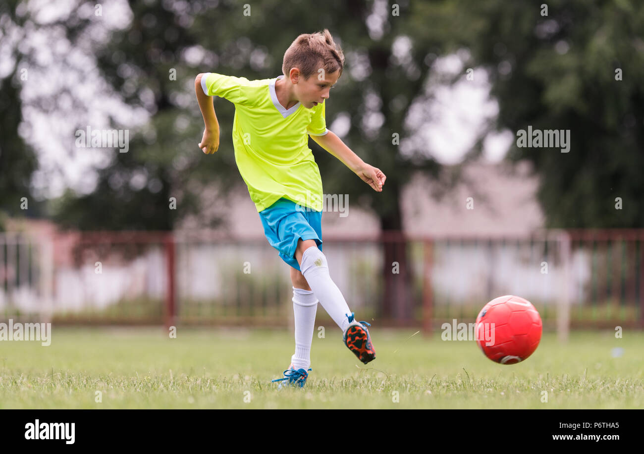 Boy kicking football on the sports field during soccer match Stock ...