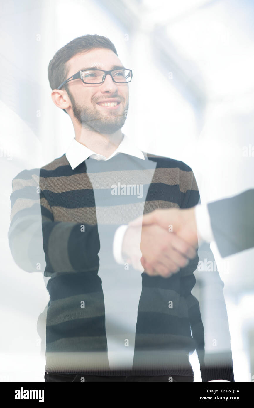 from behind the glass.handshake business people Stock Photo - Alamy