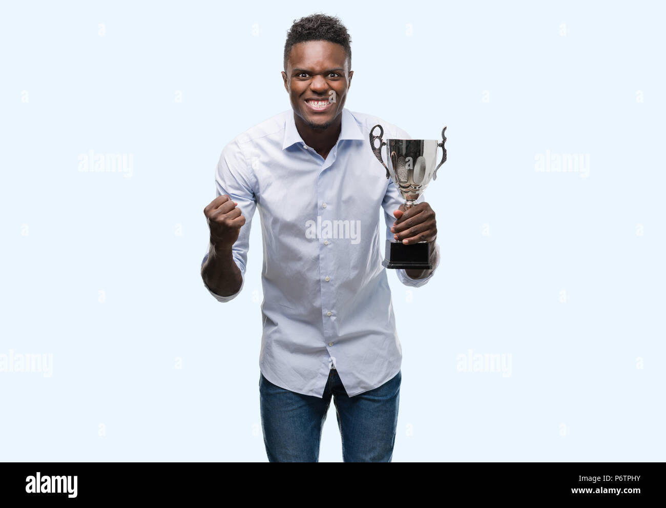 Young african american man holding trophy screaming proud and ...