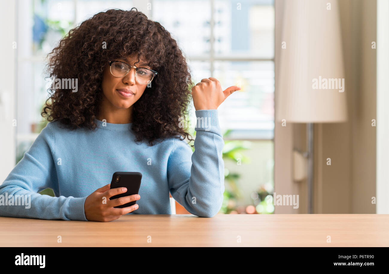 Beautiful african american woman using smartphone pointing with hand ...
