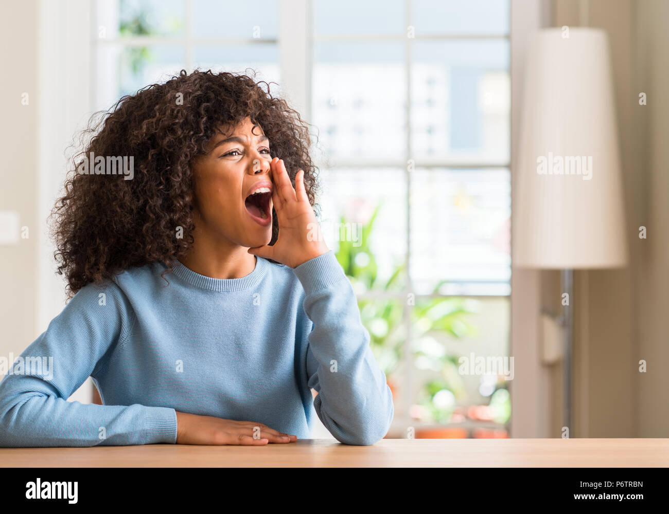 African american woman at home shouting and screaming loud to side with ...