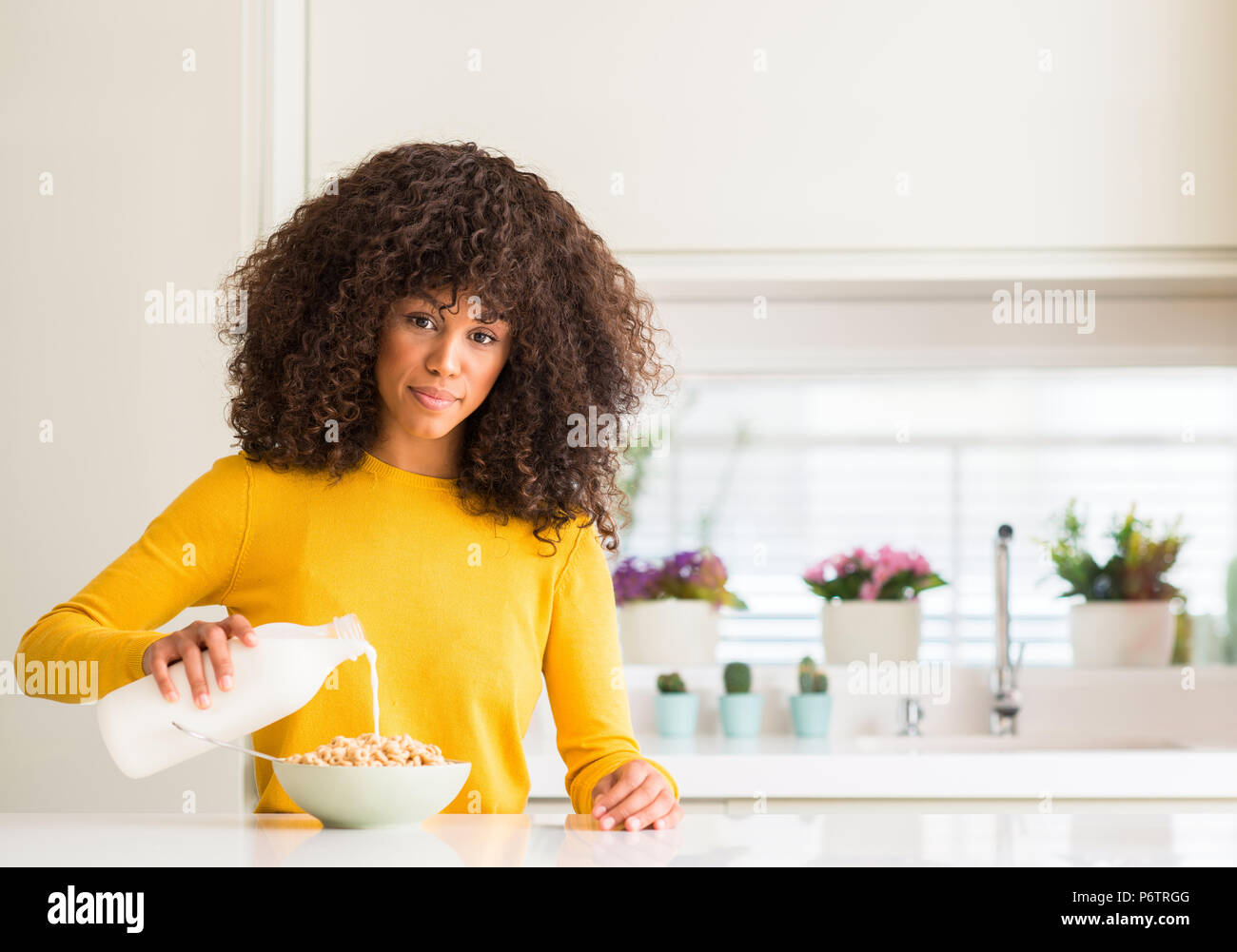 African american woman eating cereals and milk at home with a confident ...