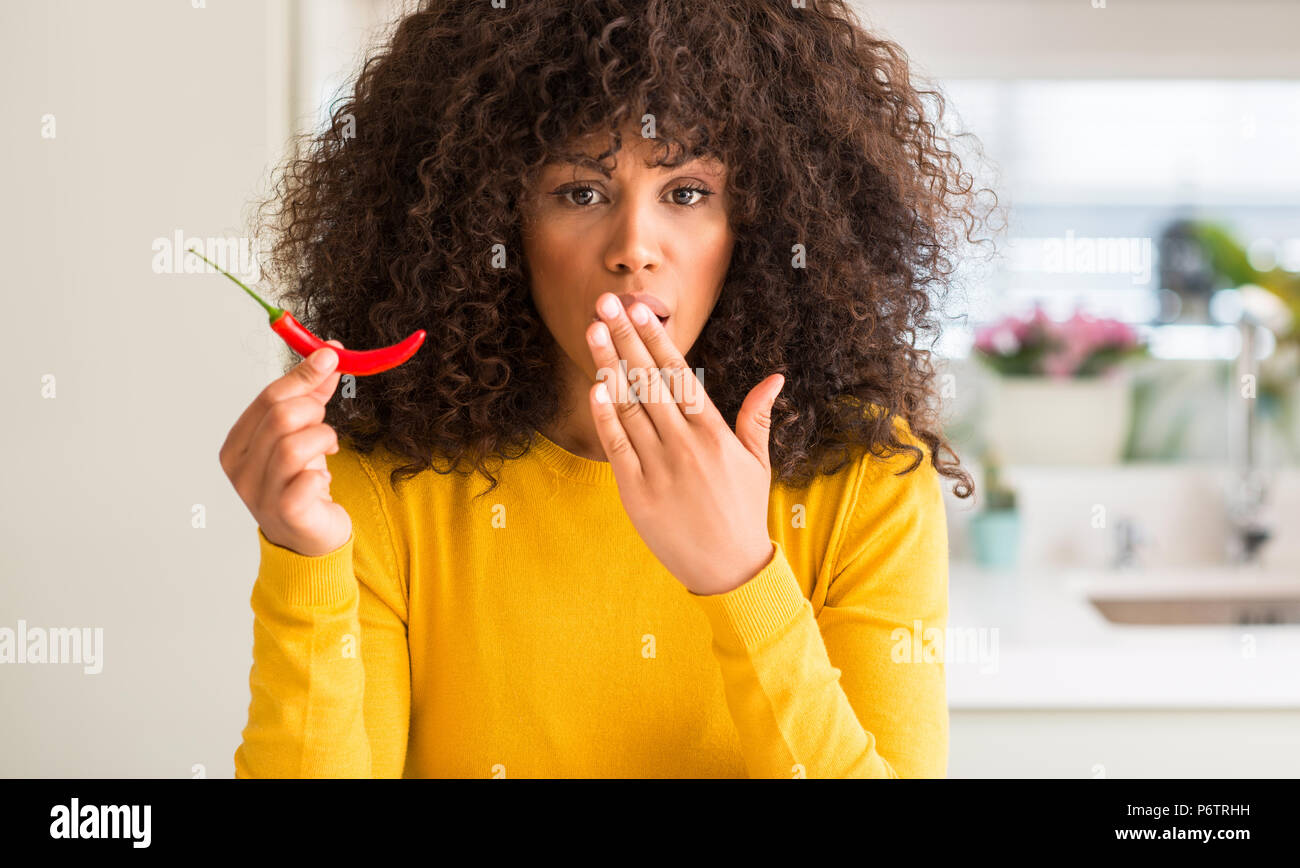 African american woman eating red hot chili pepper cover mouth with ... African american woman eating red hot chili pepper cover mouth with ...