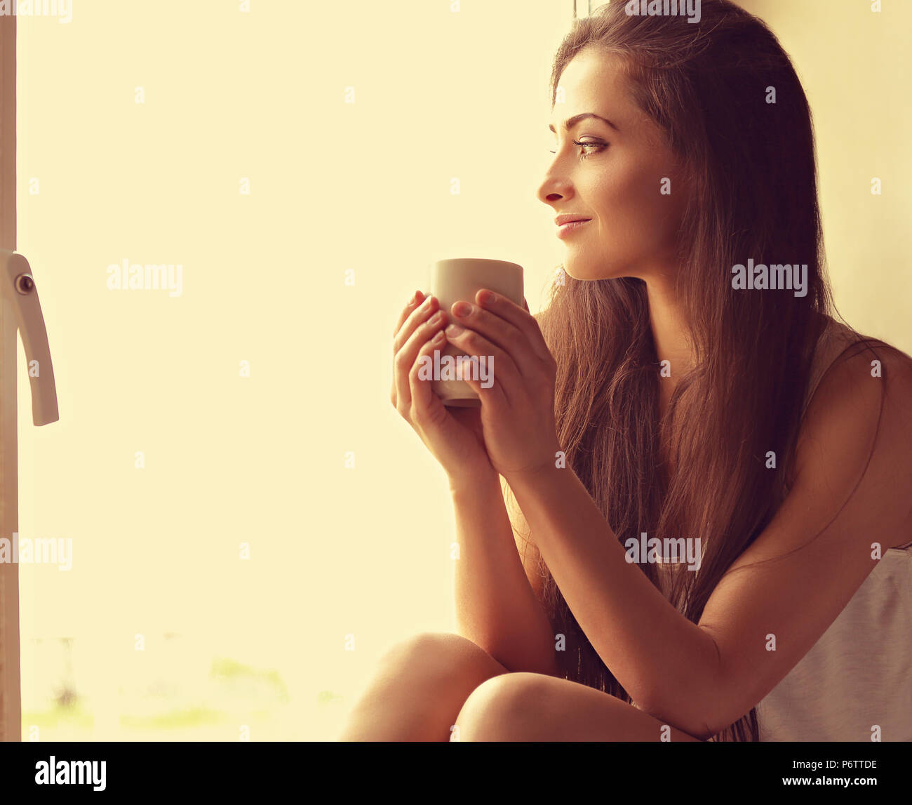 Beautiful romantic thinking woman sitting near the window and looking ...