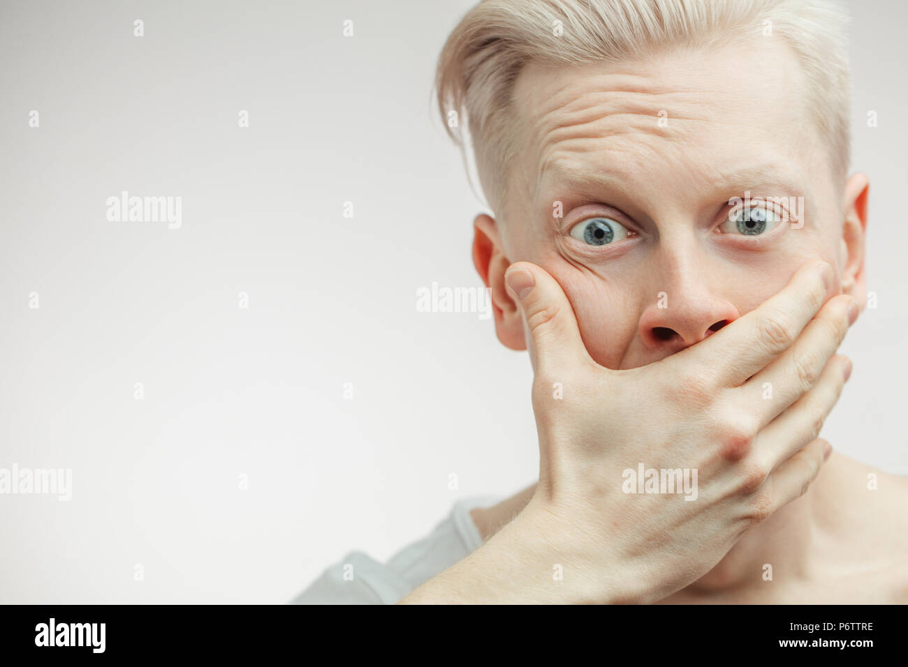 Terrified young man clutching his mouth with hands in horror as if he ...