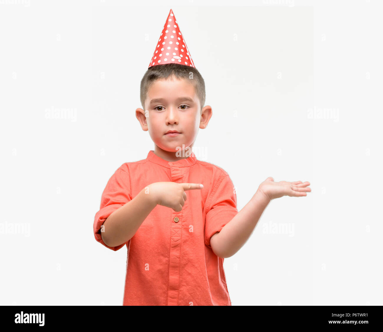 Dark haired little child wearing birthday cap very happy pointing with ...