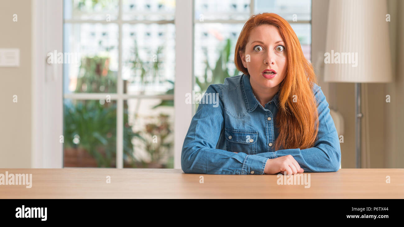 Redhead woman at home afraid and shocked with surprise expression, fear ...