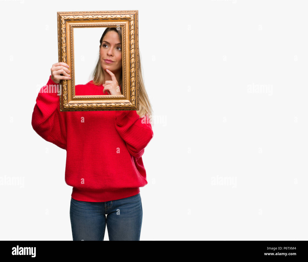 Beautiful young woman holding vintage frame serious face thinking about ...