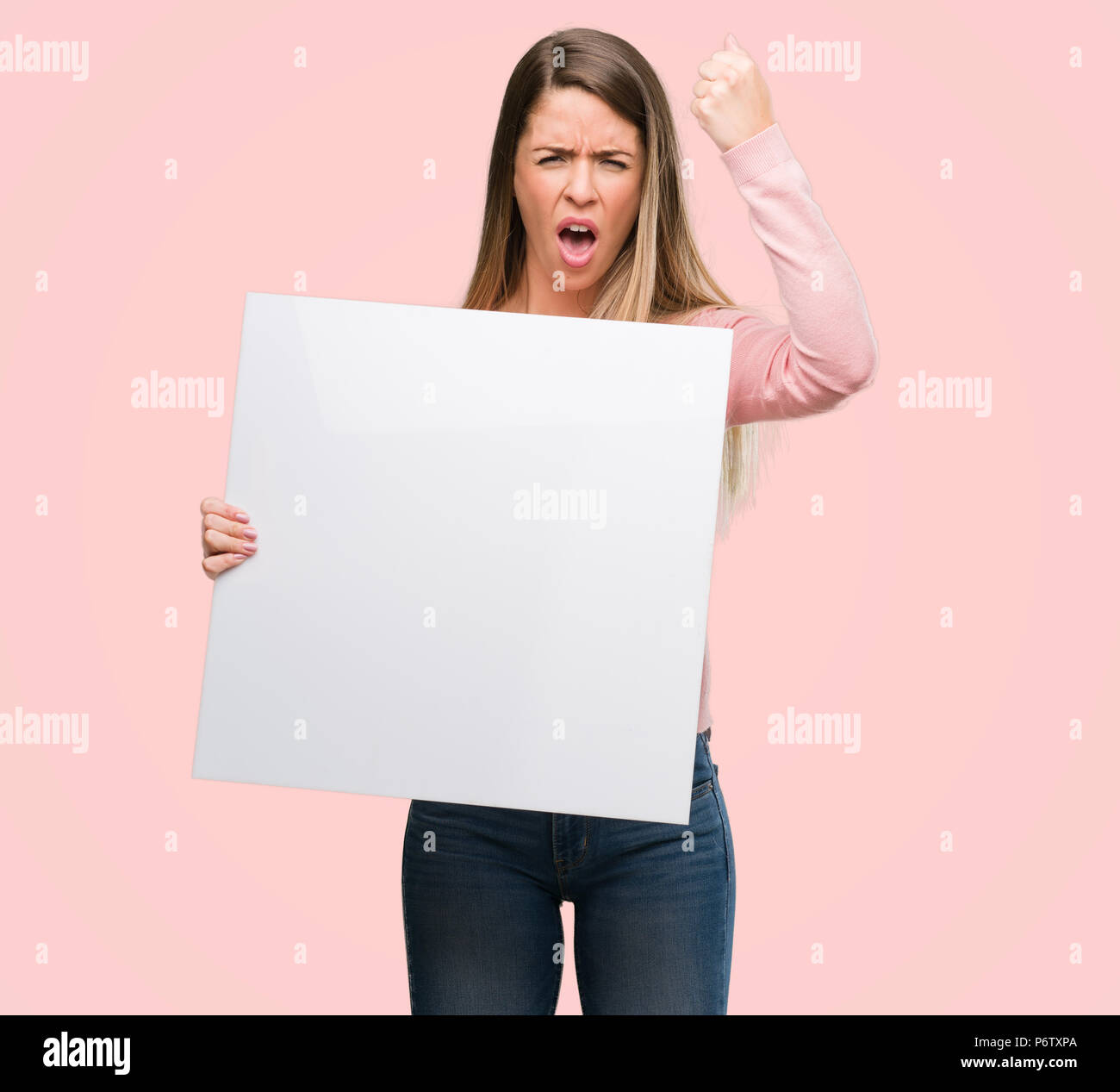 Beautiful young woman holding advertising banner annoyed and frustrated ...