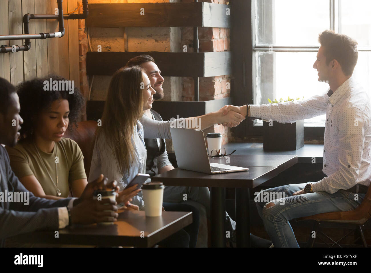 Smiling male broker greeting customers with handshake at cafe me Stock ...