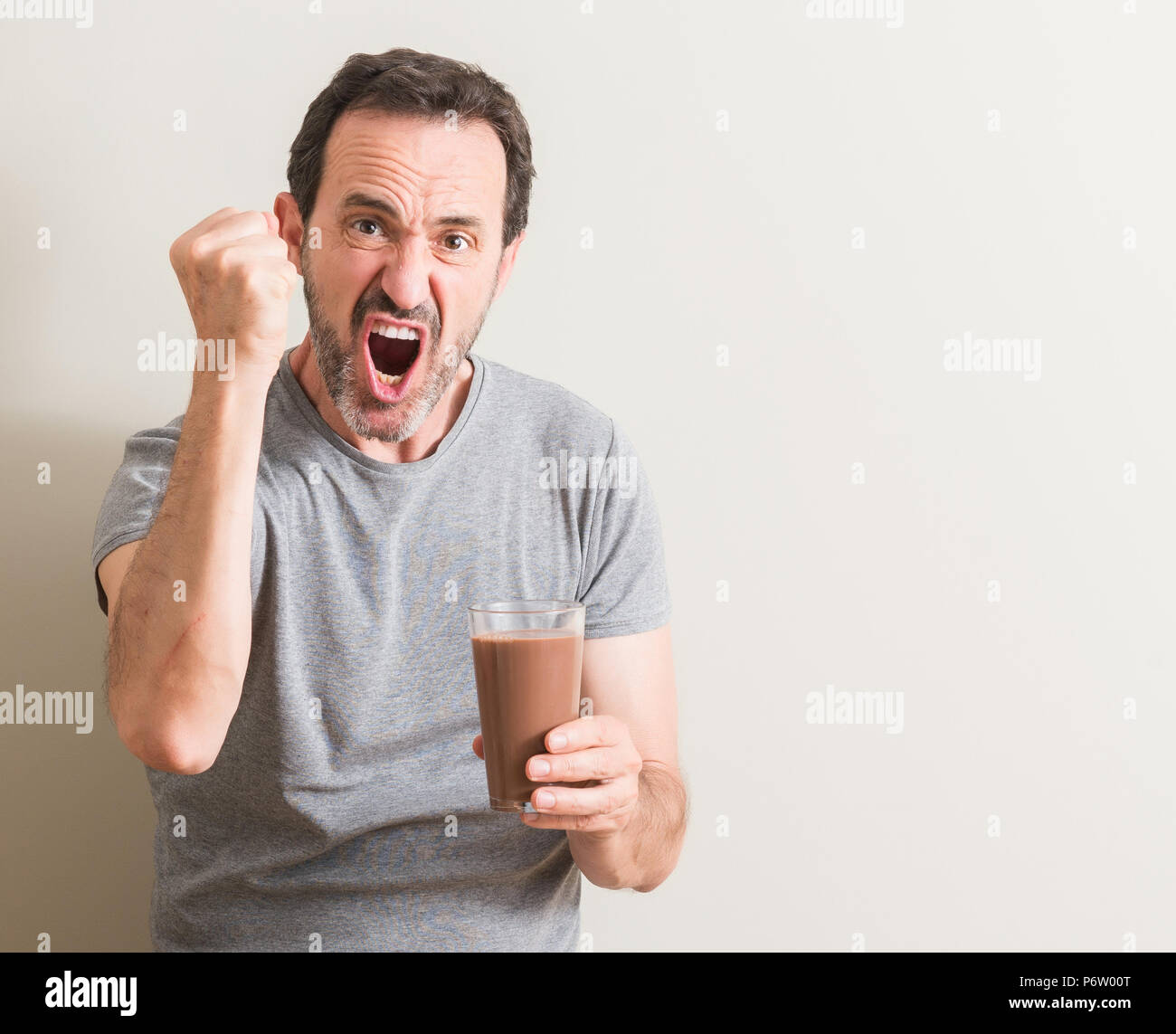 Senior man drinking chocolate milk shake annoyed and frustrated ...