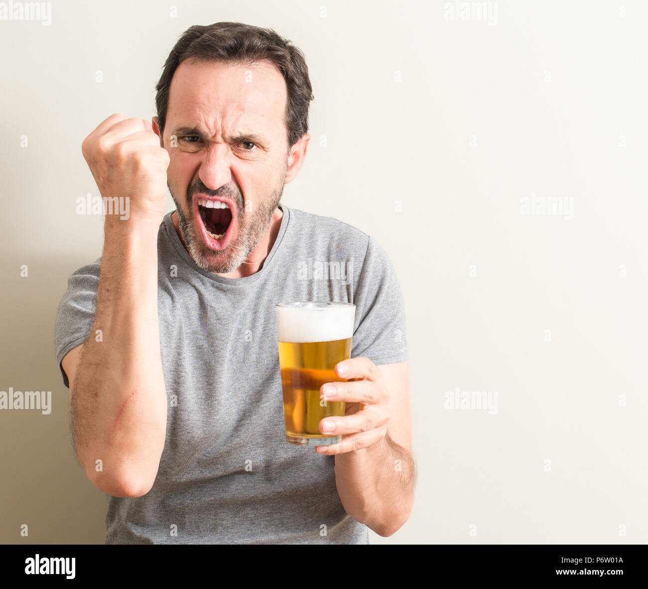 Senior man drinking beer annoyed and frustrated shouting with anger ...