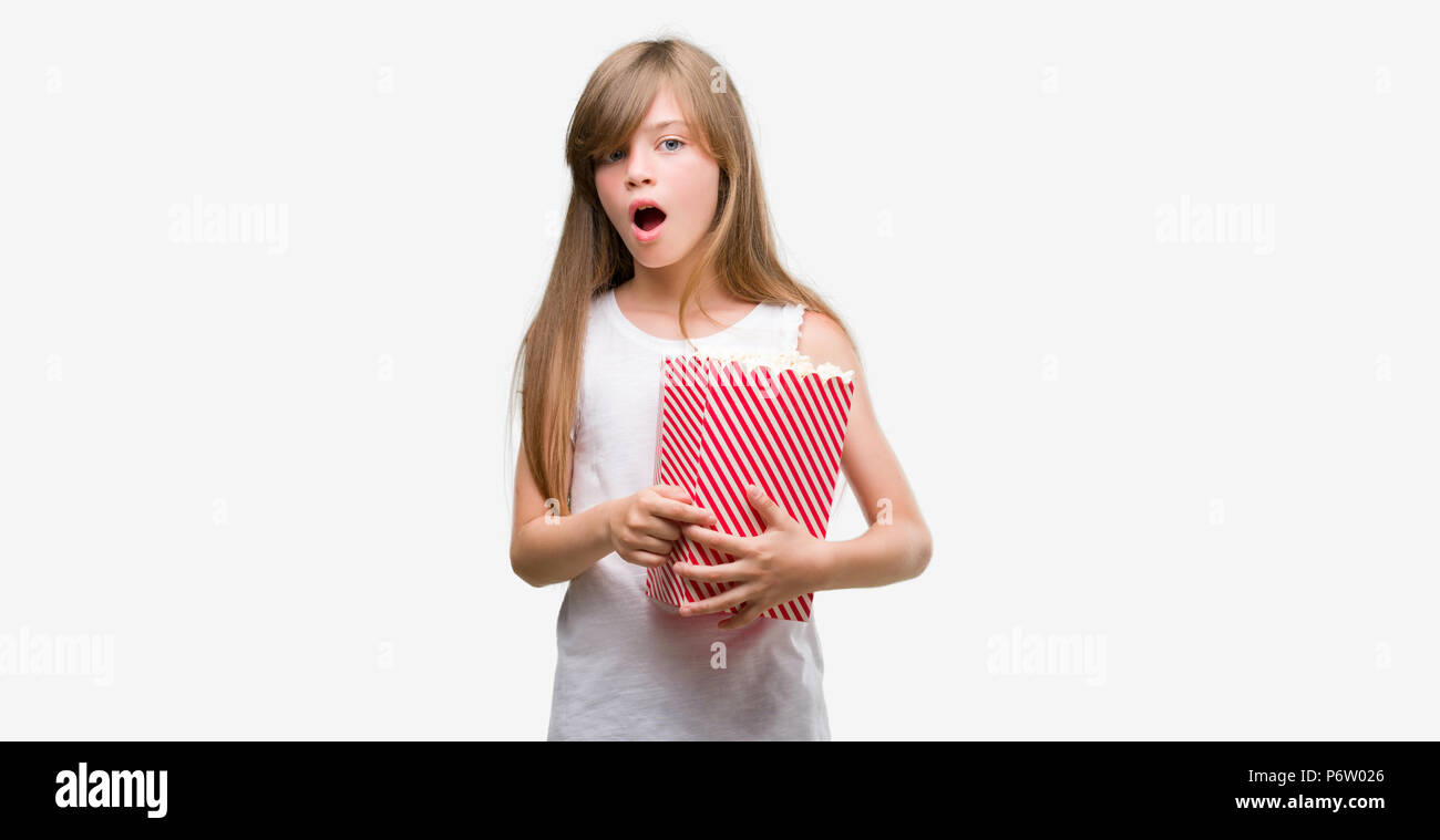 Young blonde toddler holding popcorn pack scared in shock with a ...