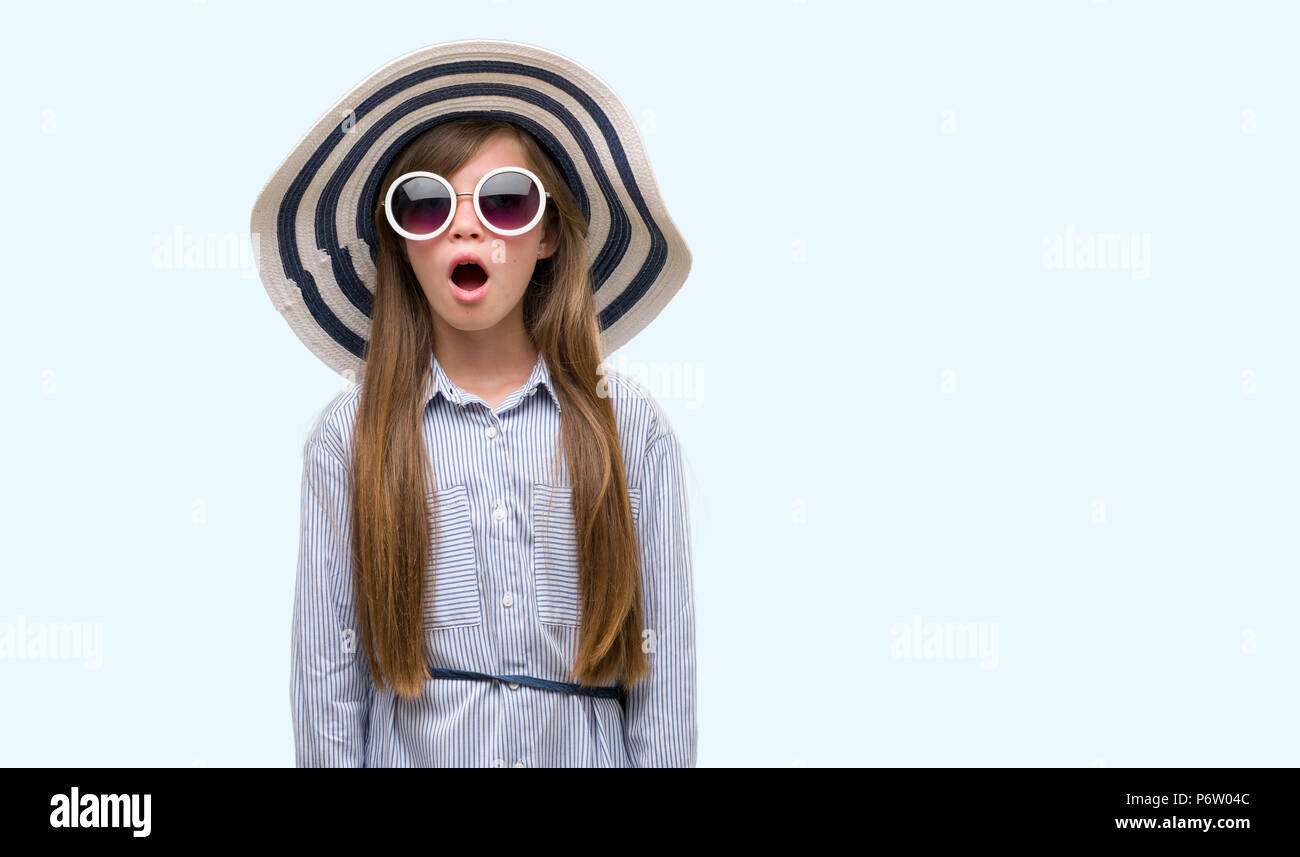 Young blonde toddler wearing hat and sunglasses scared in shock with a ...