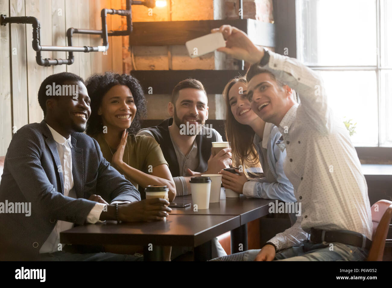 Multiracial friends smiling making selfie in cafe Stock Photo - Alamy