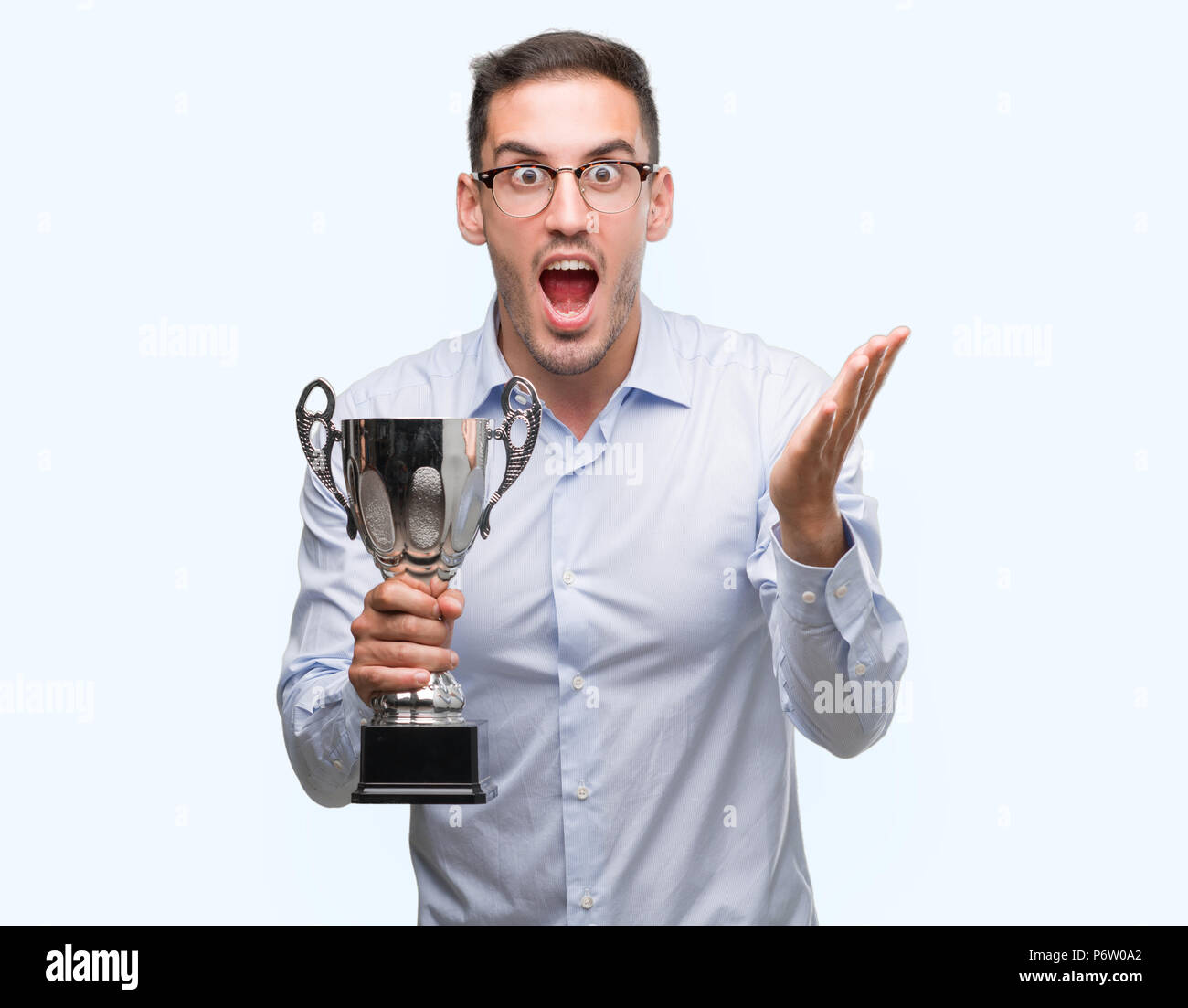 Handsome young man holding trophy very happy and excited, winner ...