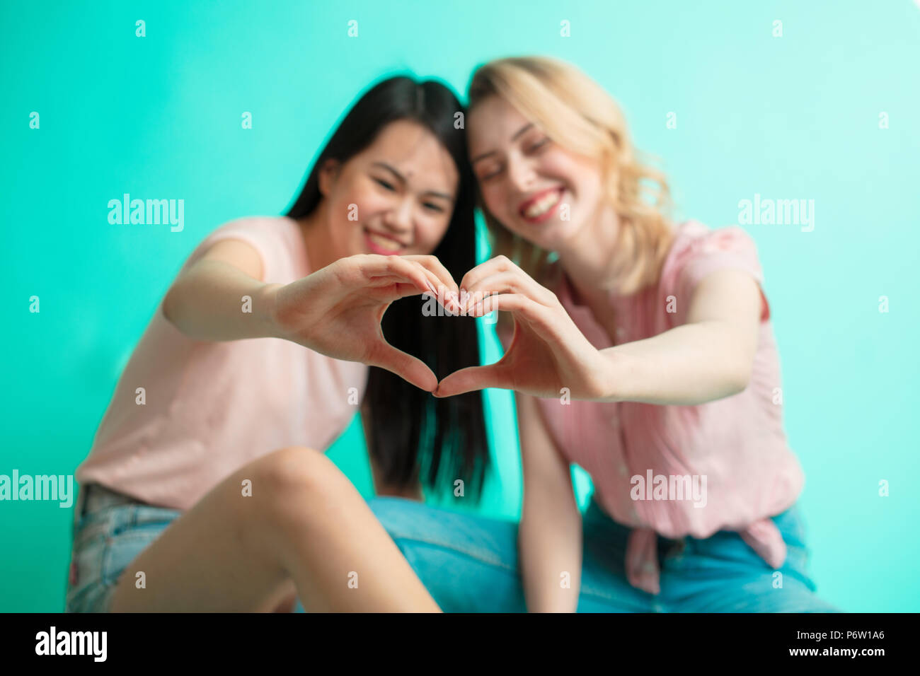 Close up of young happy girls holding their hands in heart sign with ...