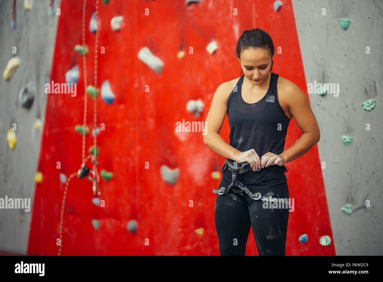 Strong athlete woman puts on belaying harness for practice on ...