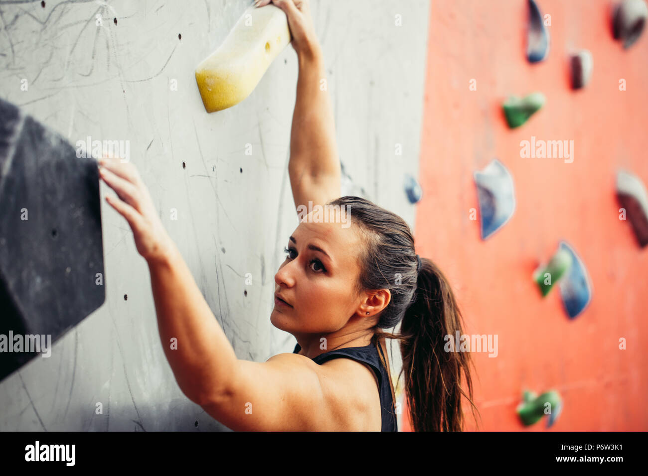 Beautiful young strong woman climbing on rock artificial wall top view ...