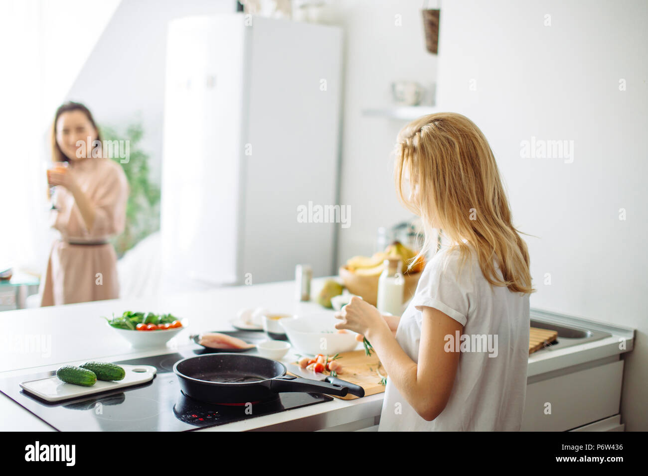 Rear view of blonde woman in white t-shirt preparing food for culinary ...