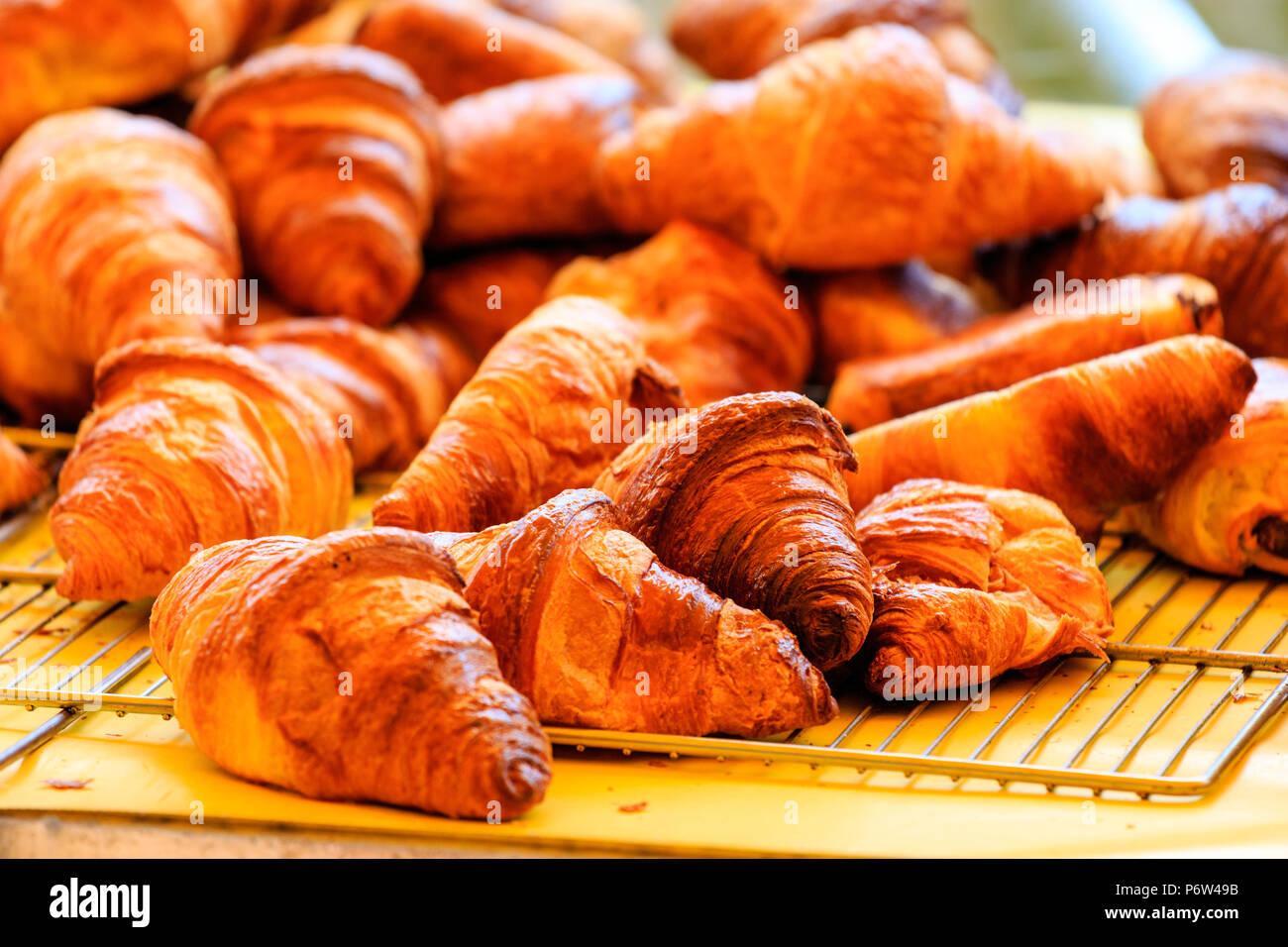 Pile of freshly baked croissants on baking rack on shop counter Stock ...