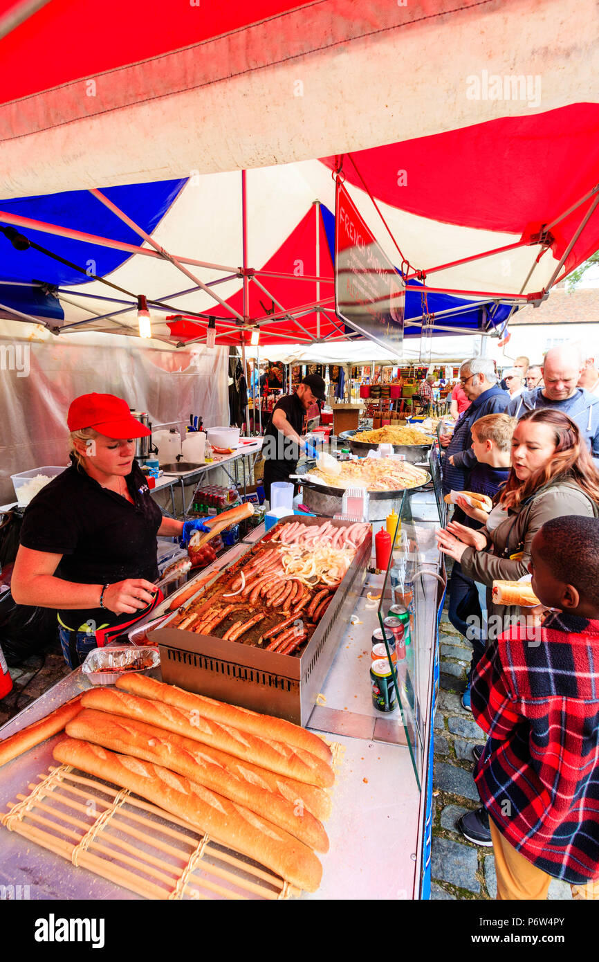 Outdoor tented covered French market stall with woman making hot dog ...
