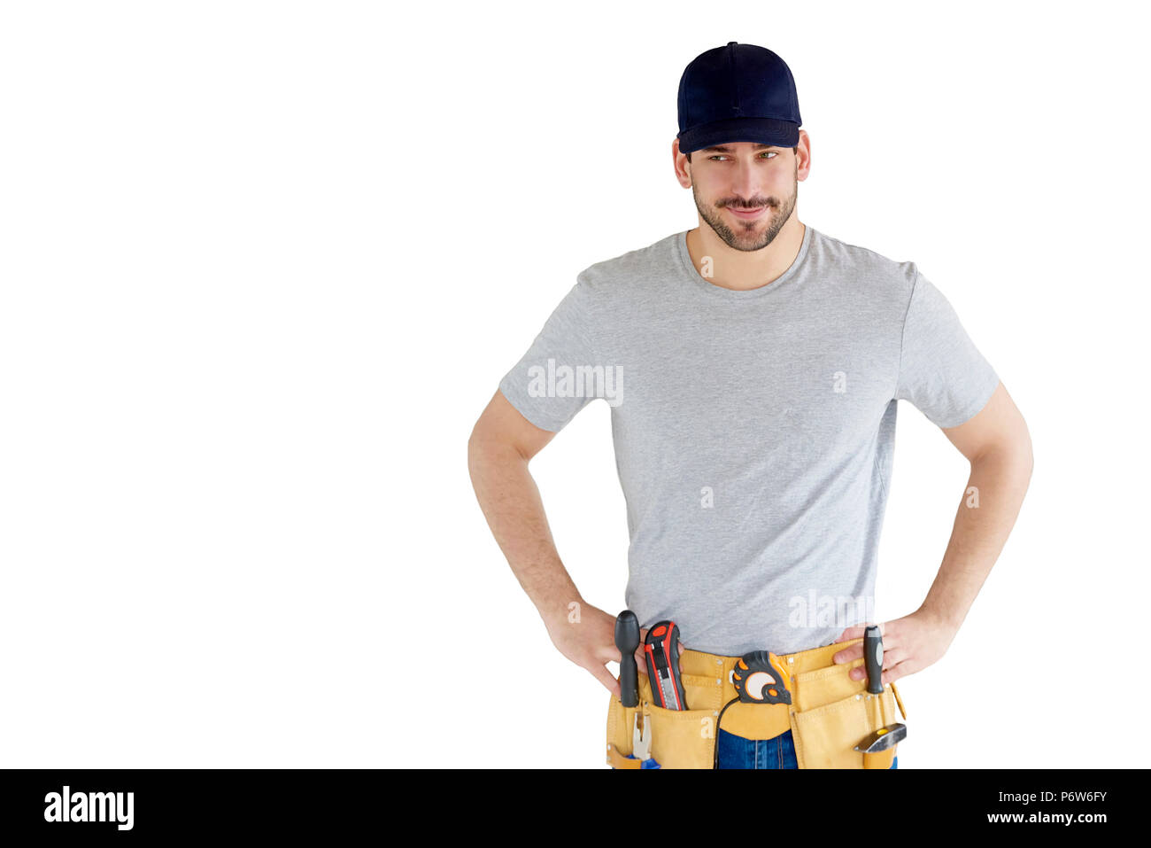 Portrait of handsome young handyman wearing baseball cap and tool belt ...