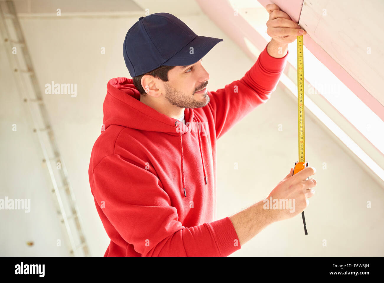 Portrait of young man using measuring tape while working on ...