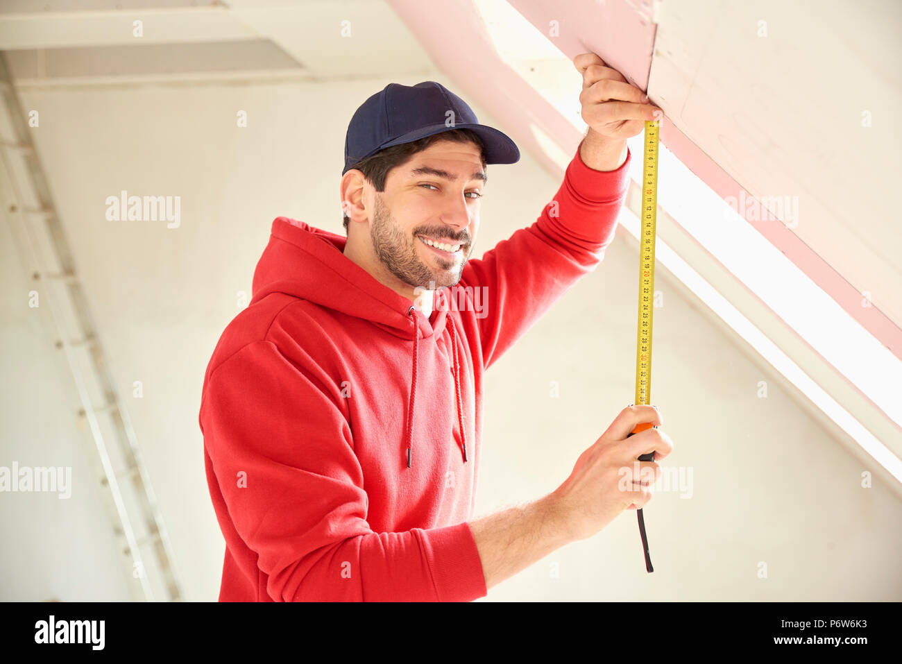 Portrait of young man using measuring tape while working on ...