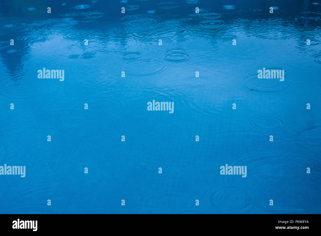 Raindrops falling on a pool or blue lake Stock Photo - Alamy