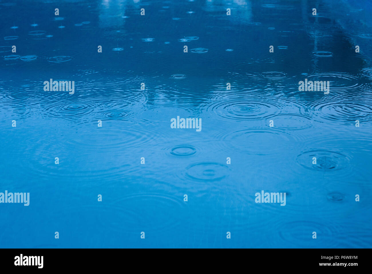 Raindrops falling on a pool or blue lake Stock Photo - Alamy